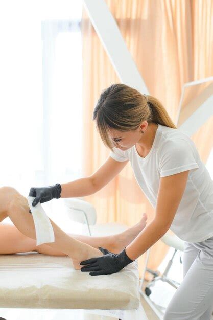Premium Photo | Beautician waxing female legs in spa center