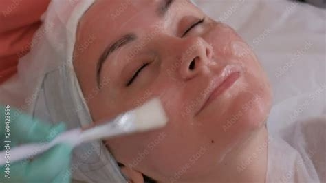 The cosmetologist's hand applies the gel to the female face with a ...