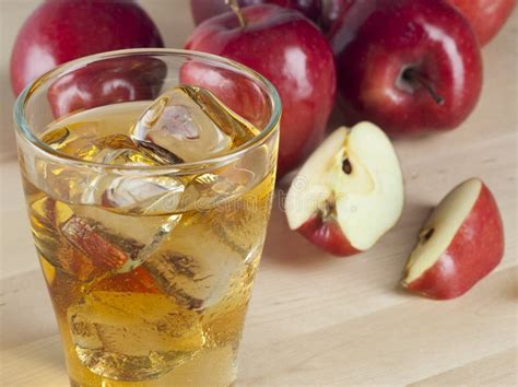 A Glass of Fresh Cold Apple Juice with Ice beside Apples on a Wooden ...