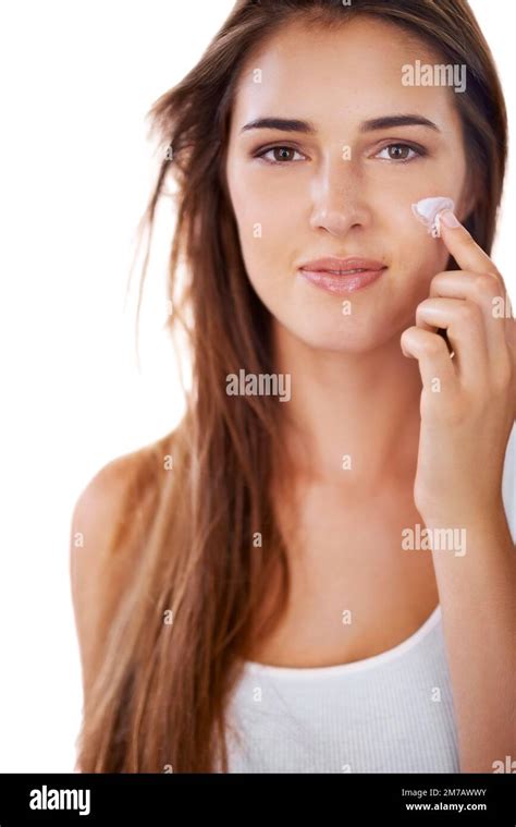 Deep moisturizing. a beautiful woman applying moisturizer to her face ...