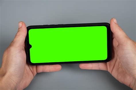Premium Photo | Hands holding the phone horizontally green chroma key mockup on smartphone