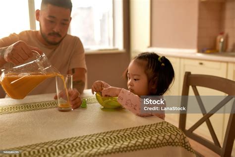 Father Pour Juice In Cup While Her Daughter Eat Stock Photo - Download Image Now - Adult ...