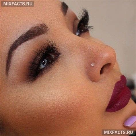 a woman with long lashes and purple lipstick looks up at the camera ...