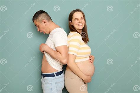 Funny Young Couple Wearing Casual Clothing Standing Together with Bare Bellies Comparing Size of ...
