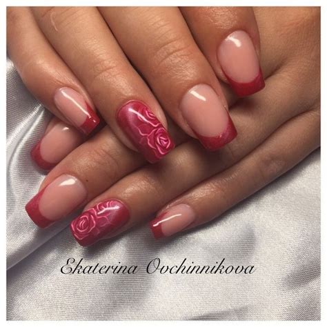 a woman's hands with red and pink nail polishes on their nails,