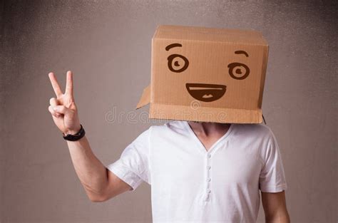 Молодой человек Gesturing с картонной коробкой на его головке с Smiley ...