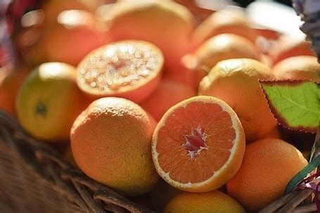 Фото Апельсины лежащие в вазе, один из которых почищен и разделен на дольки
