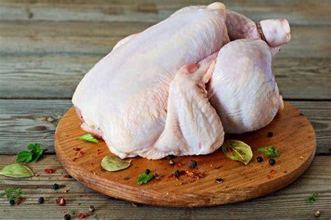 Сырая куриная тушка готова к приготовлению на разделочной доске на ...