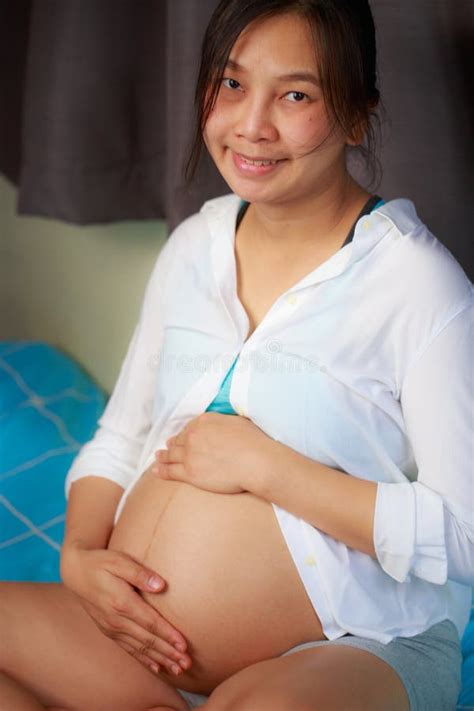 Pregnant Woman Smiling while Sitting on Bed, Showcasing Her Belly Stock Image - Image of ...
