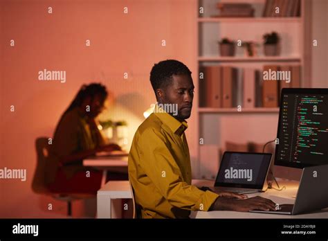 Portrait of African-American IT developer writing code on multiple ...