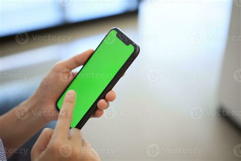 Phone green screen in hand, hand holding smartphone green screen in house, using mobile phone ...