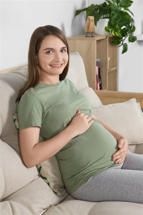 Happy Pregnant Woman Sitting on Sofa and Touching Her Belly in Living ...