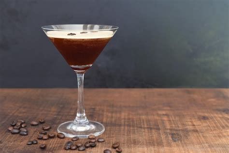 Copa de espresso martini con granos de café en la mesa de madera y fondo negro | Foto Premium