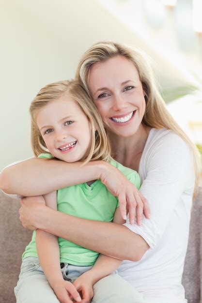 Premium Photo | Mother hugging her daughter on couch