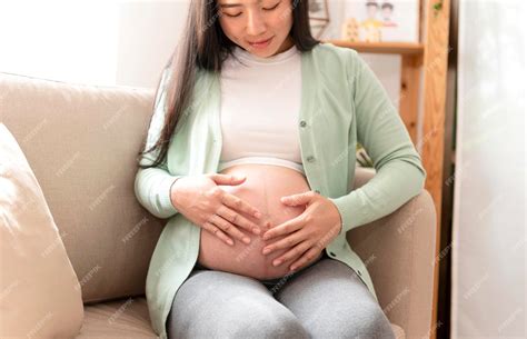 Free Photo | Young asian beautiful pregnant woman hands fondle on belly sitting on sofa at home