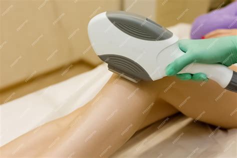Premium Photo | Beautician removes hair on beautiful female legs using ...