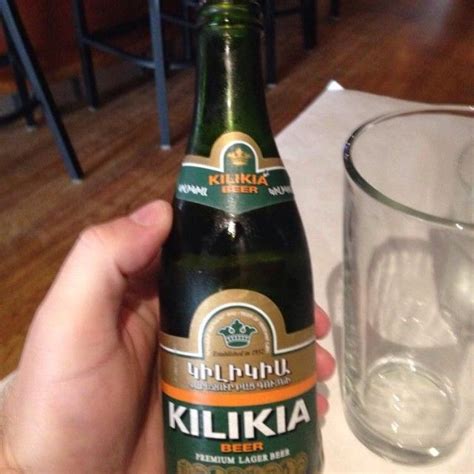 a person holding up a bottle of beer next to a glass