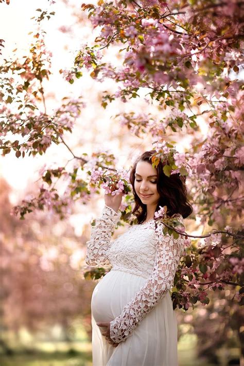 a pregnant woman standing under a tree with pink flowers